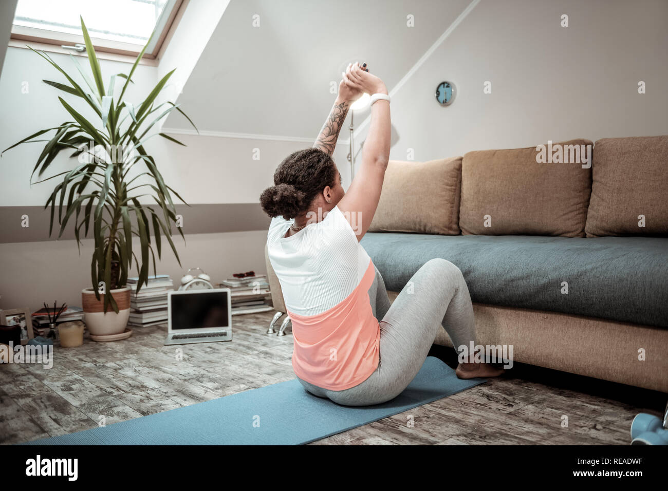 Dark-haired woman raising her hands while swinging press Stock Photo ...
