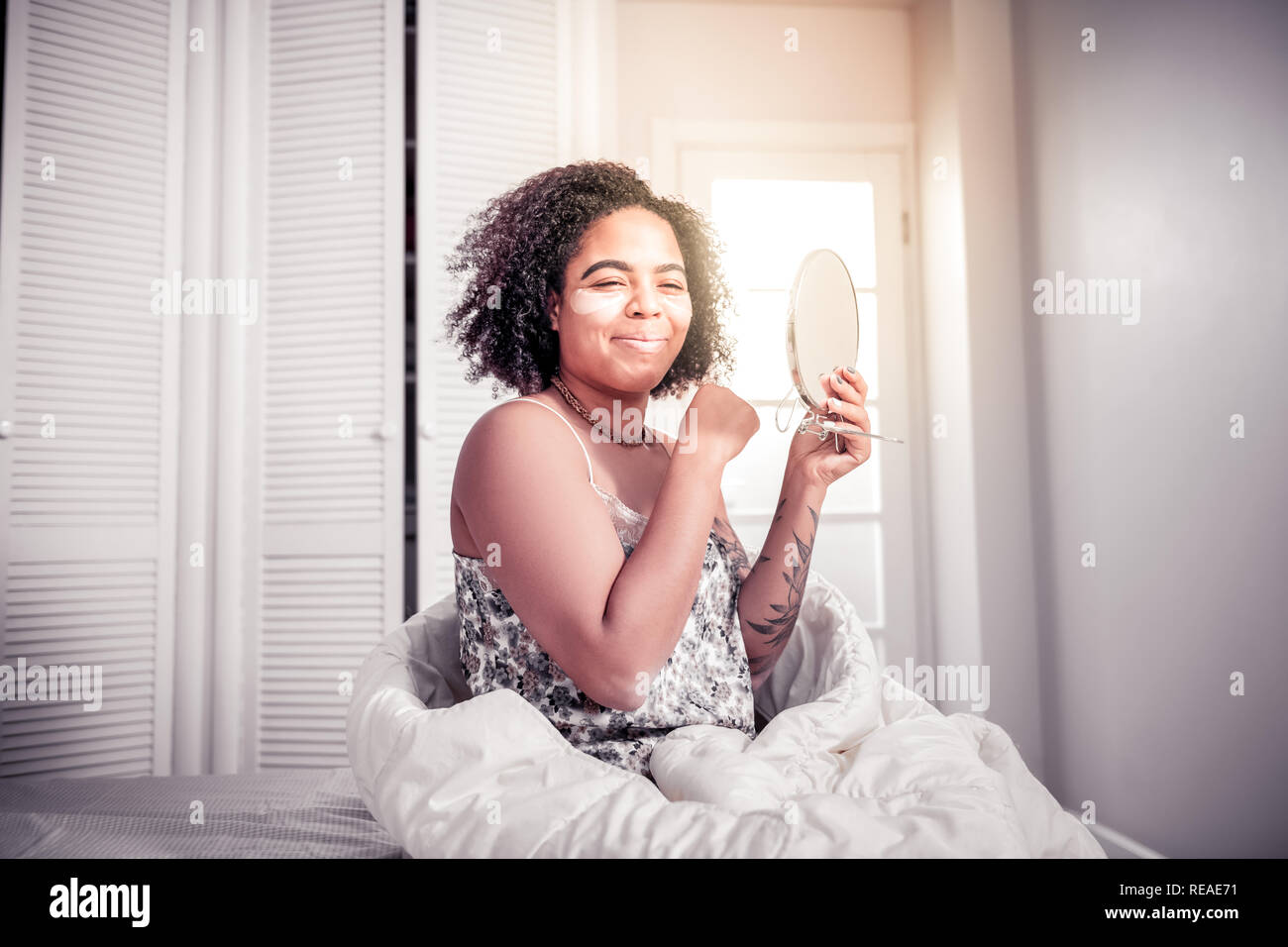 Contented young lady sitting in her bed covered with blanket Stock ...