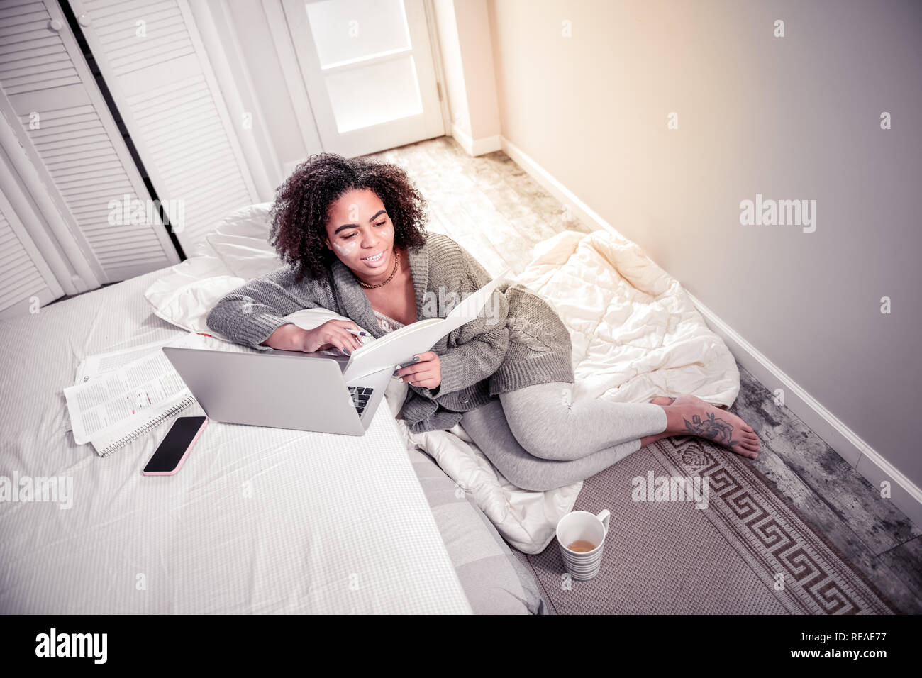 Short-haired dark-skinned woman examining papers while working at home ...