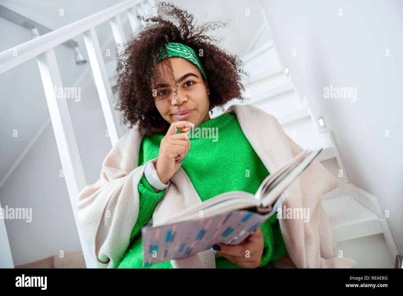 Funky young lady eating snacks and reading book Stock Photo - Alamy