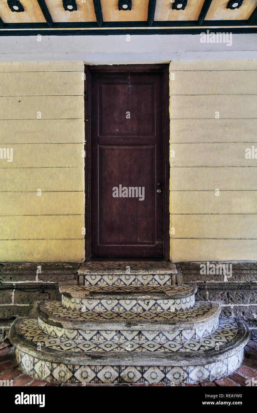 Closed wooden door of a plinth house upon a four-step flight of tile ...