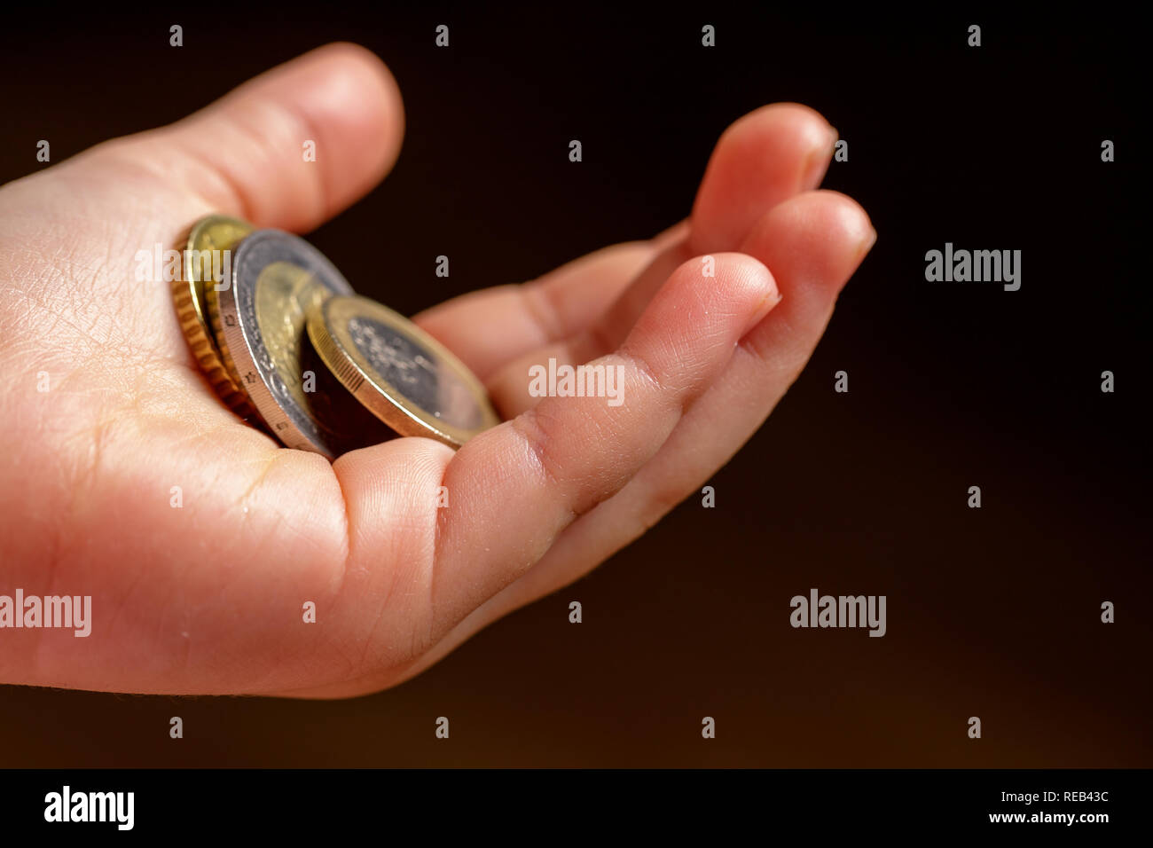 Child holding euro coin in his hand. Pocket money stock image. Poor low ...