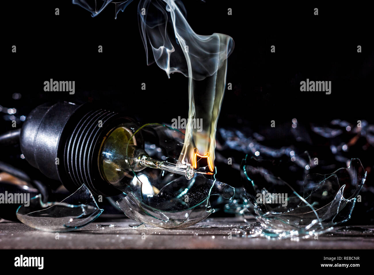 amazing explosion of a burning light bulb with splinters and smoke on a ...
