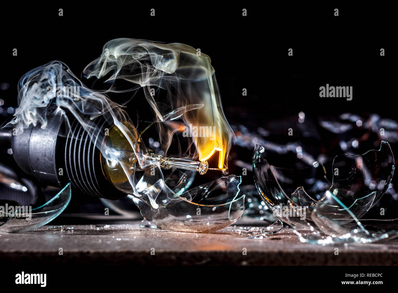 amazing explosion of a burning light bulb with splinters and smoke on a ...