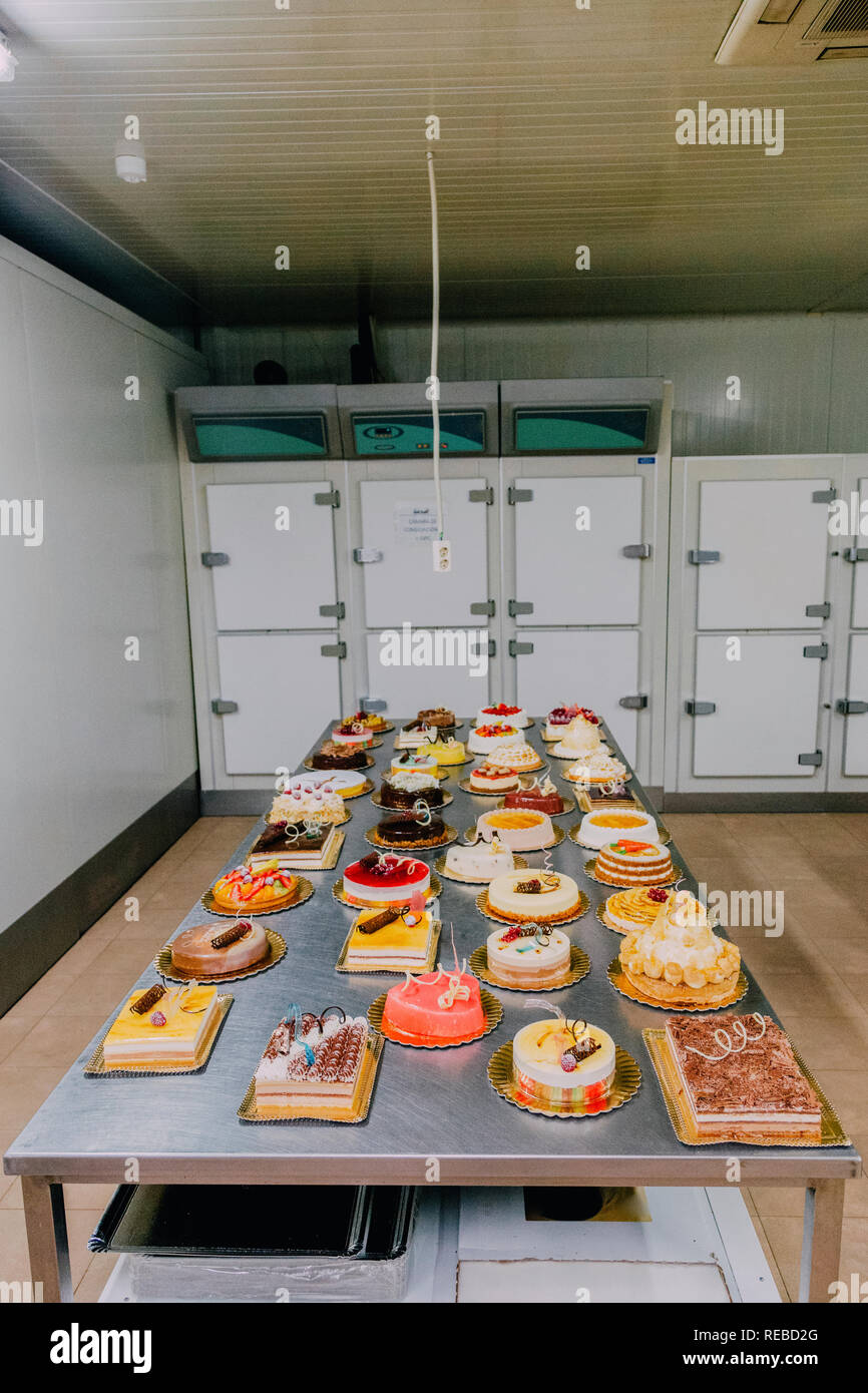 many different cakes prepared on the metal table of a food factory ...