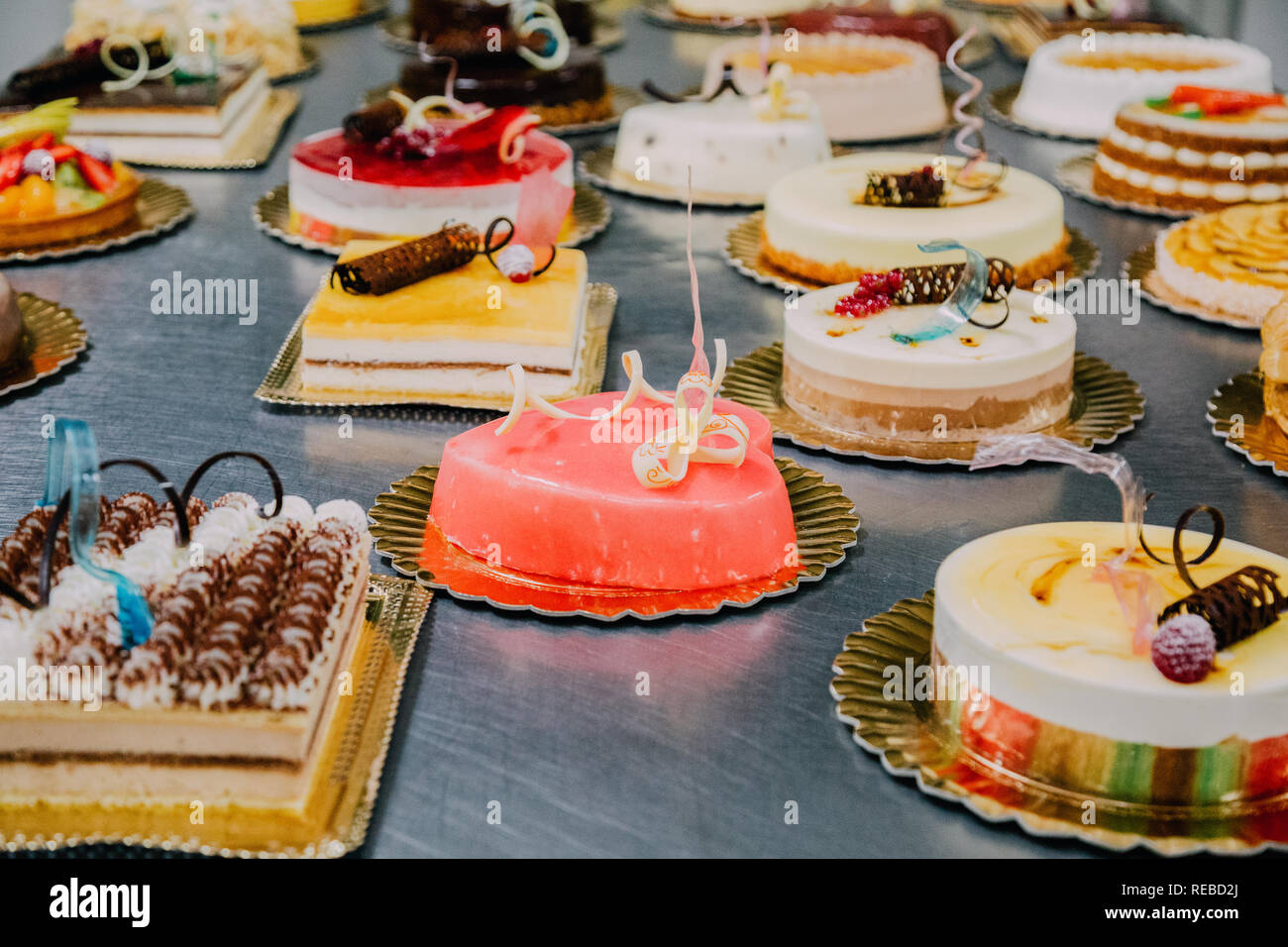 many different cakes prepared on the metal table of a food factory ...