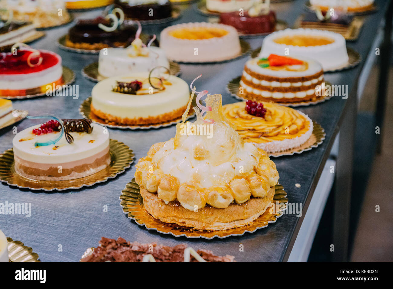 many different cakes prepared on the metal table of a food factory ...