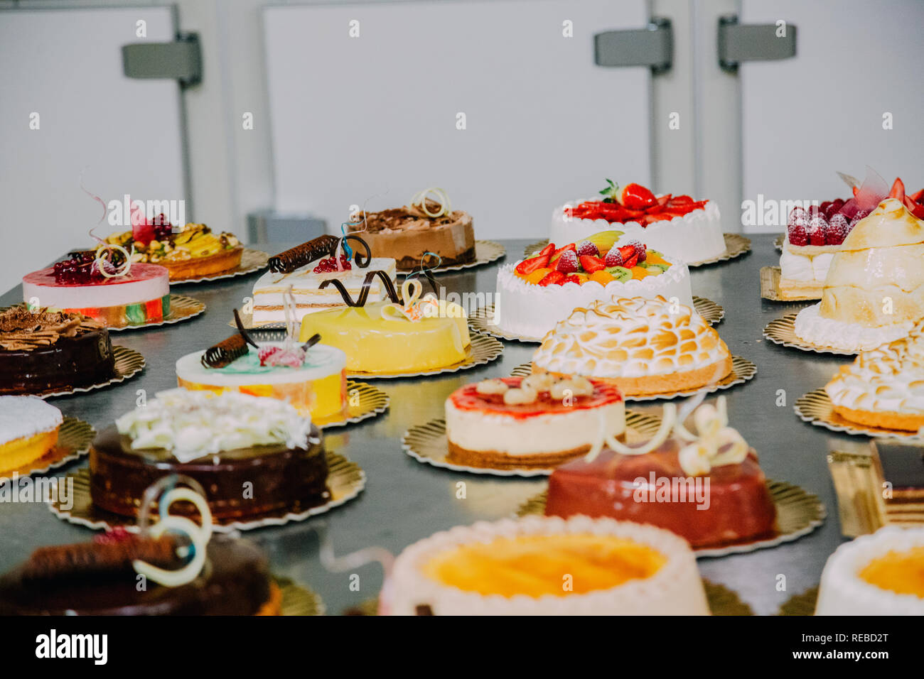 many different cakes prepared on the metal table of a food factory ...