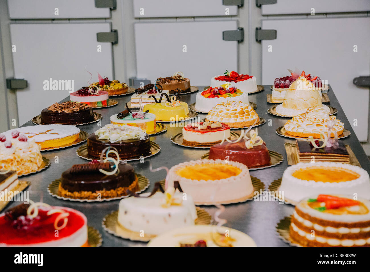 many different cakes prepared on the metal table of a food factory ...