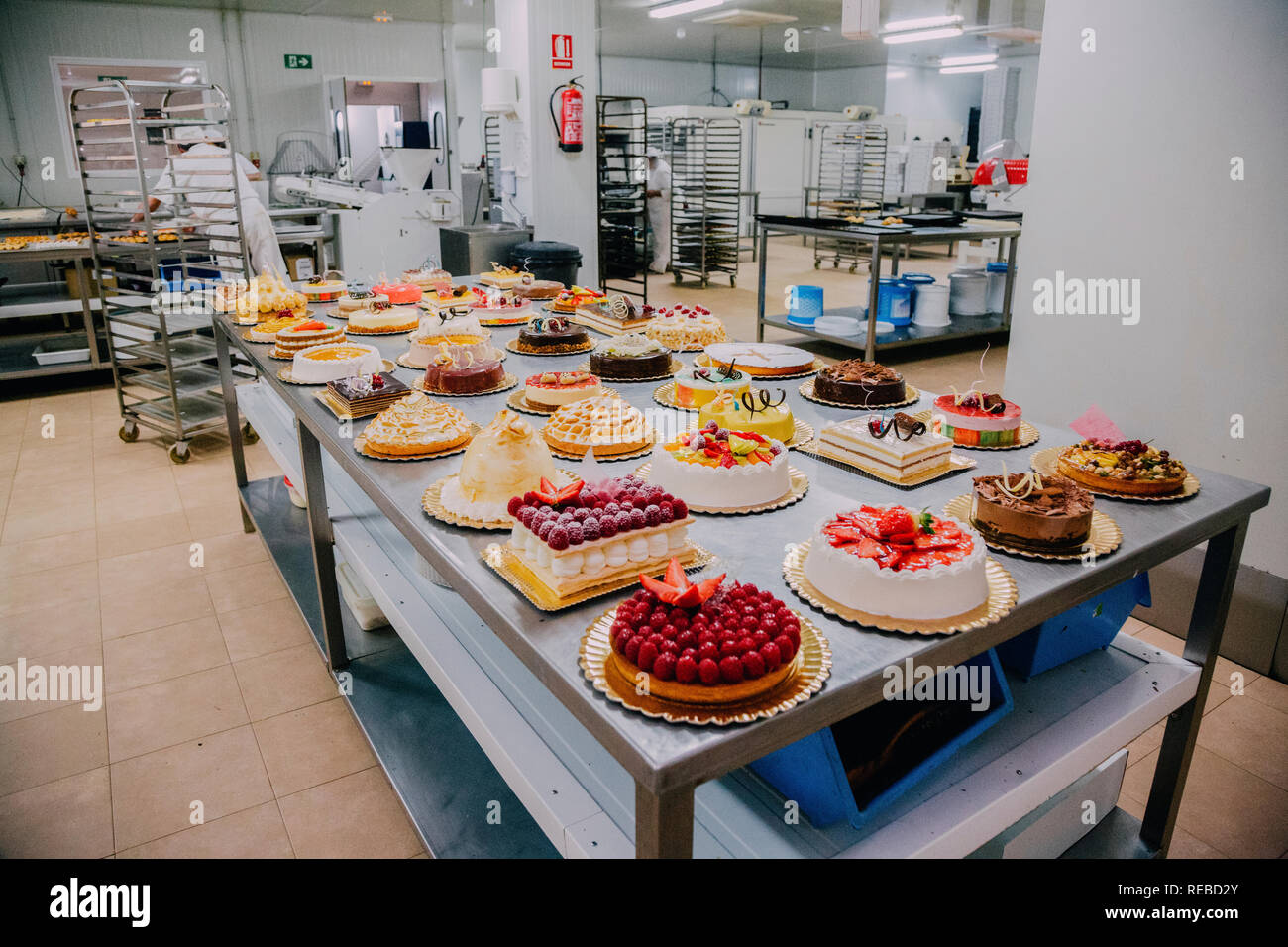 many different cakes prepared on the metal table of a food factory ...