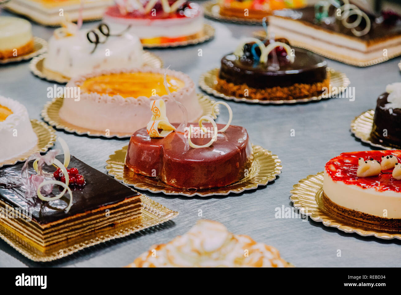 many different cakes prepared on the metal table of a food factory ...
