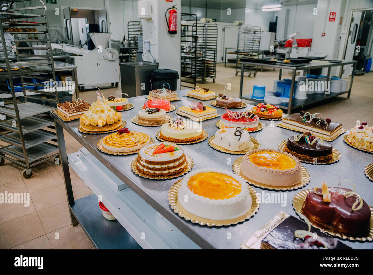 many different cakes prepared on the metal table of a food factory ...