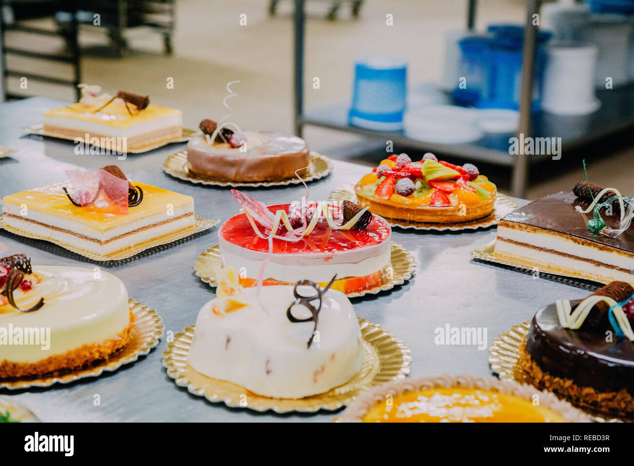 many different cakes prepared on the metal table of a food factory ...