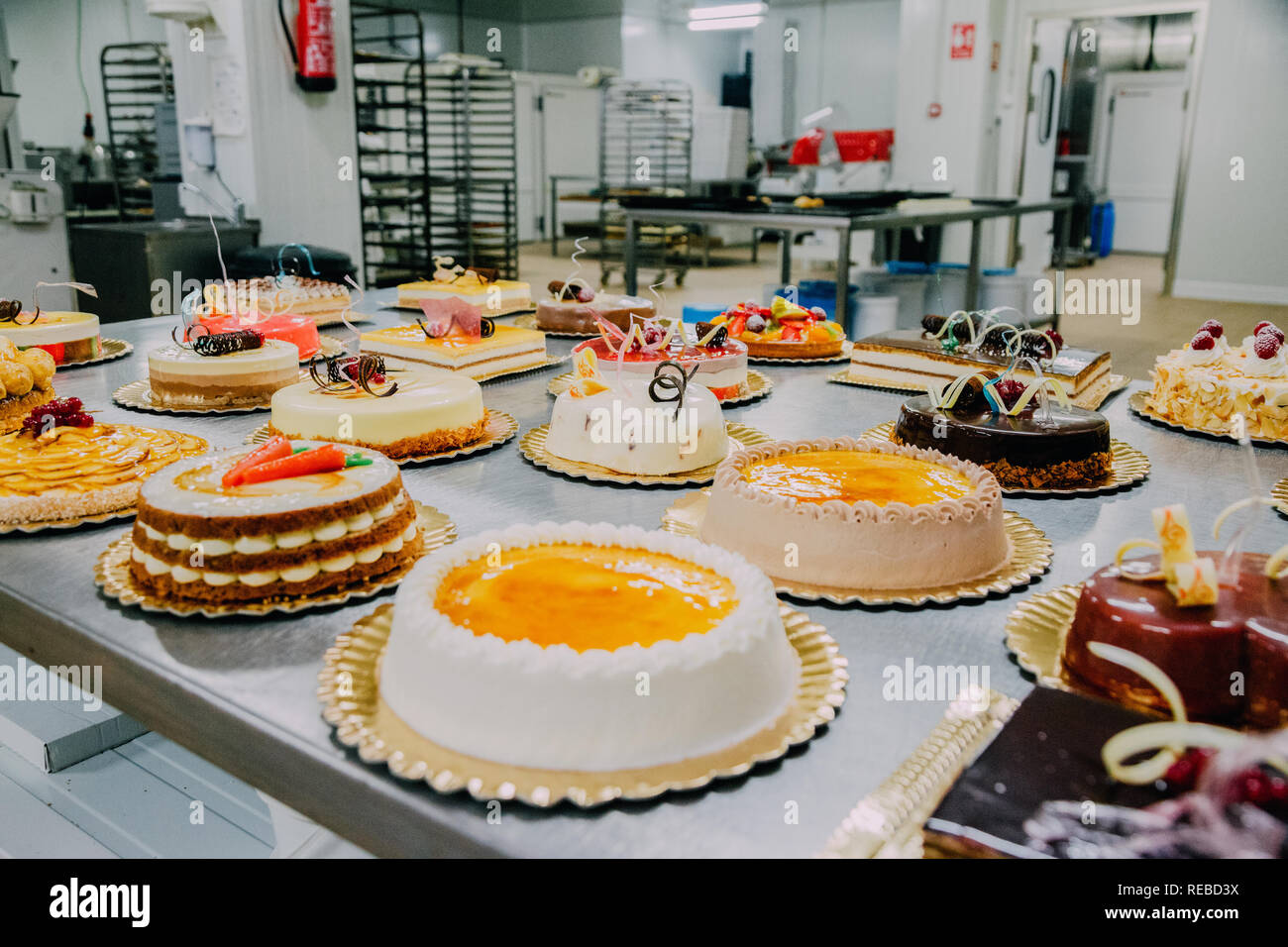 many different cakes prepared on the metal table of a food factory ...