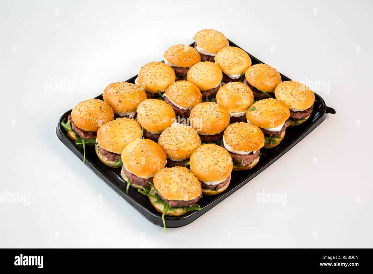 small burgers on a black tray prepared to takeaway on white background ...