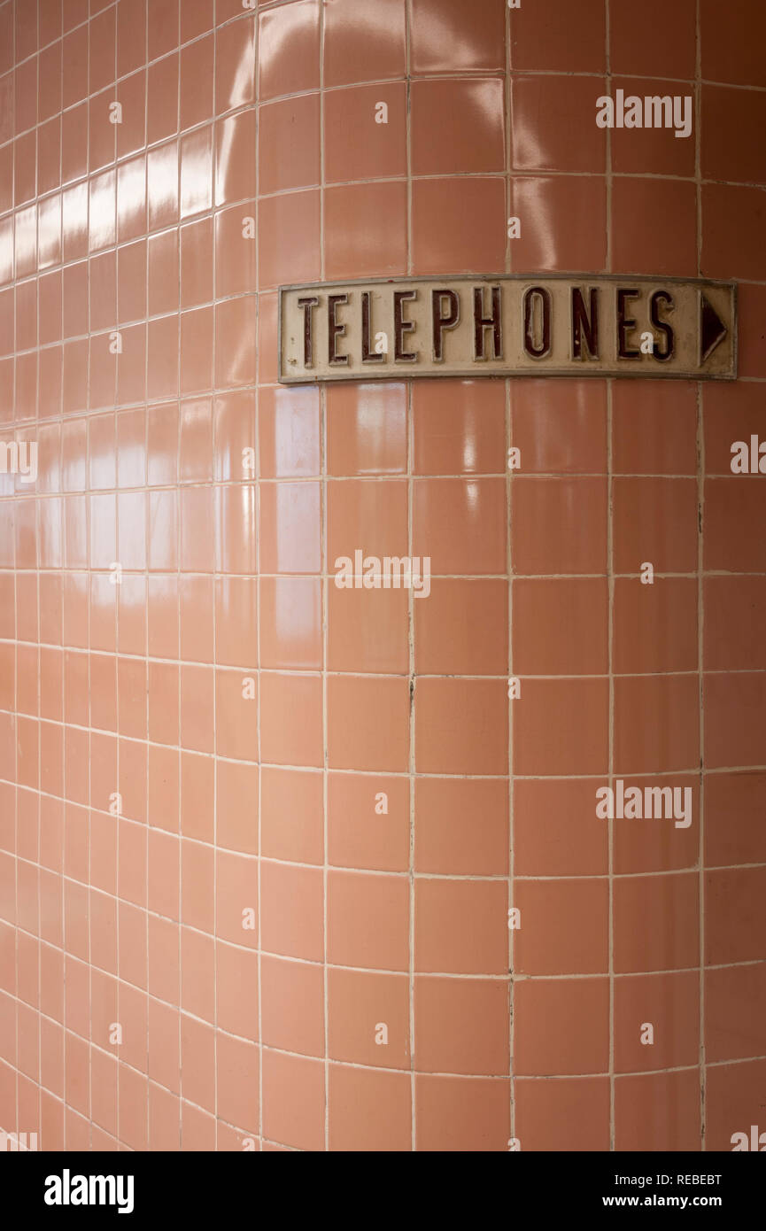 An old Telephone sign on a salmon colored tile wall in an old ...