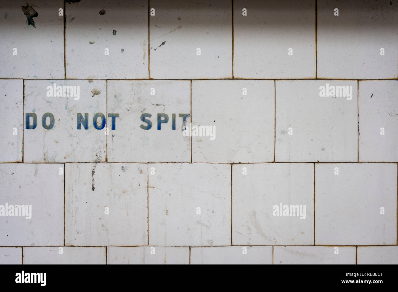 dirty white subway tiles with the words Do Not Spit painted as a ...