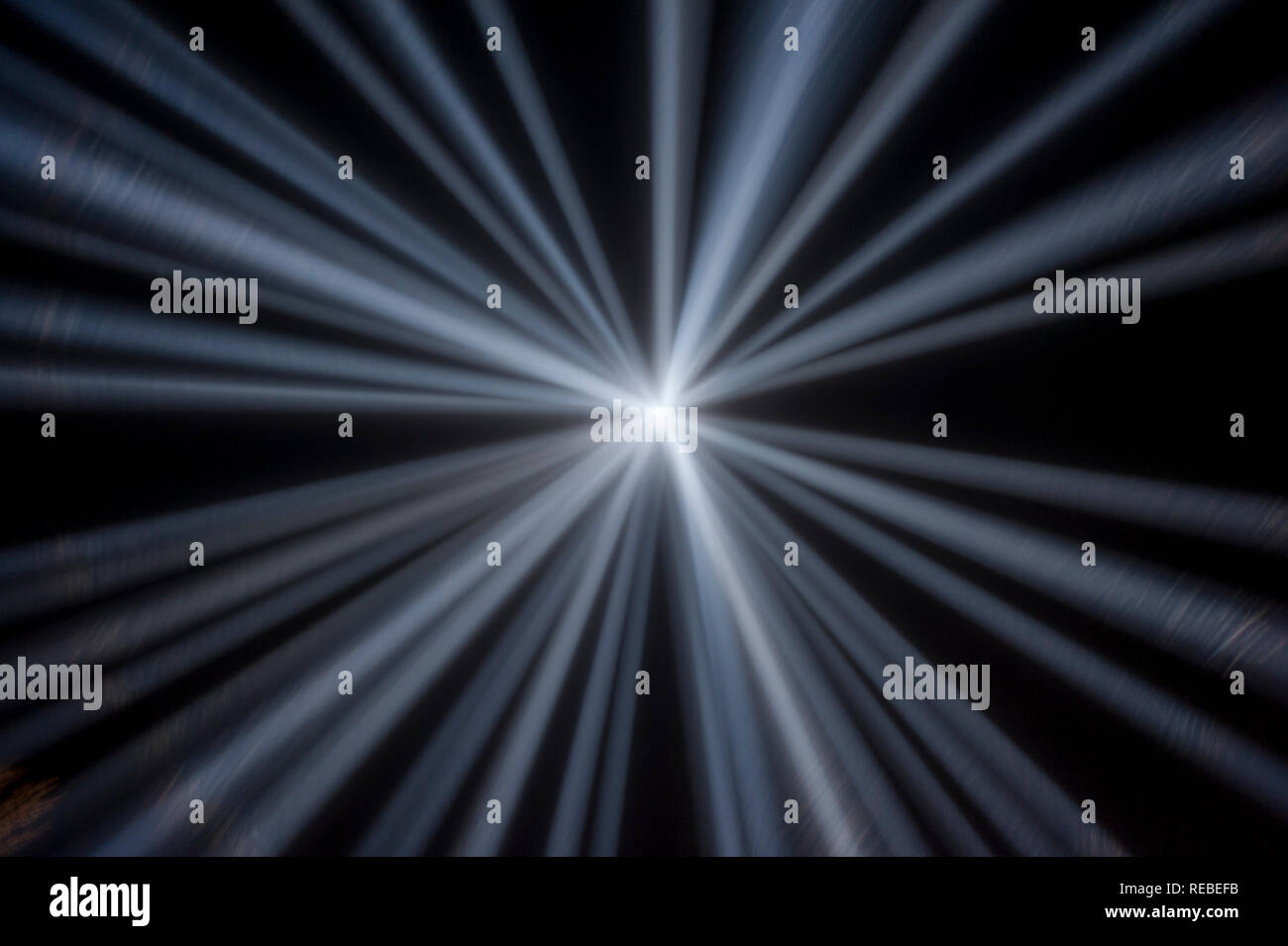 Multiple white spotlights shining up into a black night sky, converging ...
