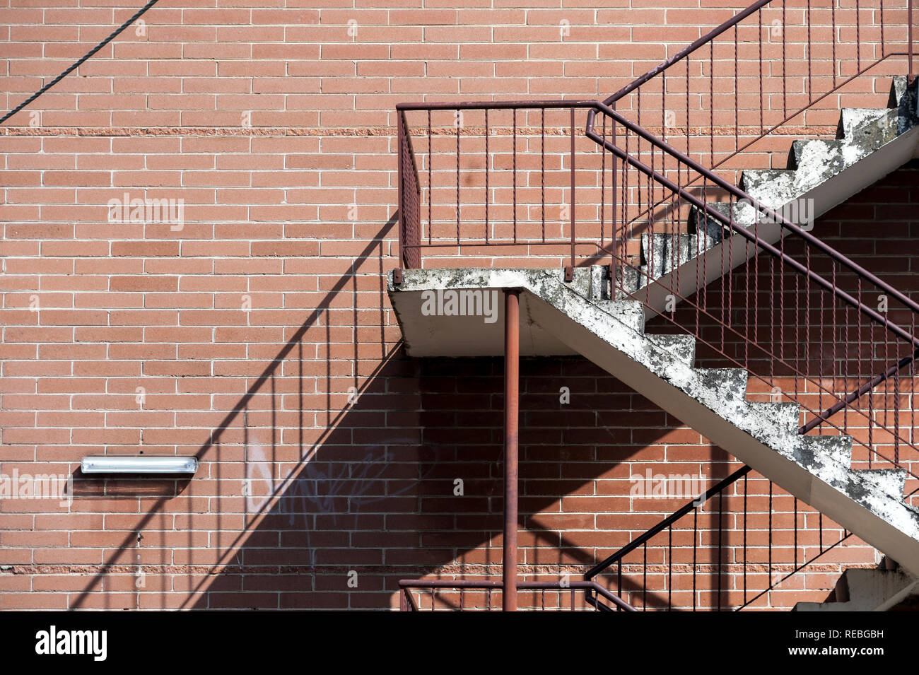 Concrete stairs with red metal railings against a red brick wall ...