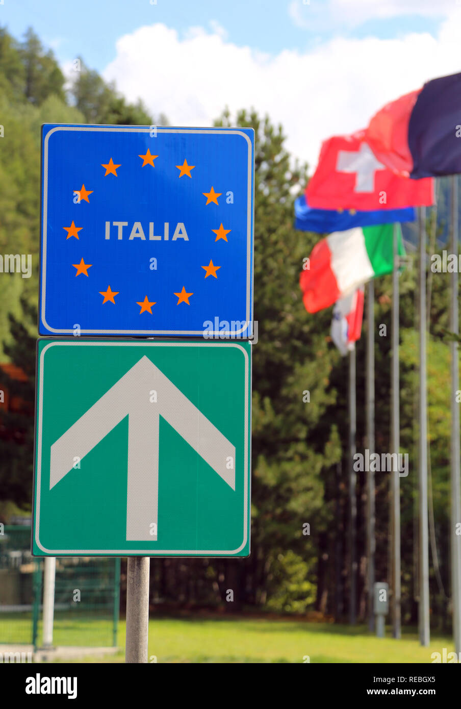 road sign of the Italian border direction with flags on the background ...