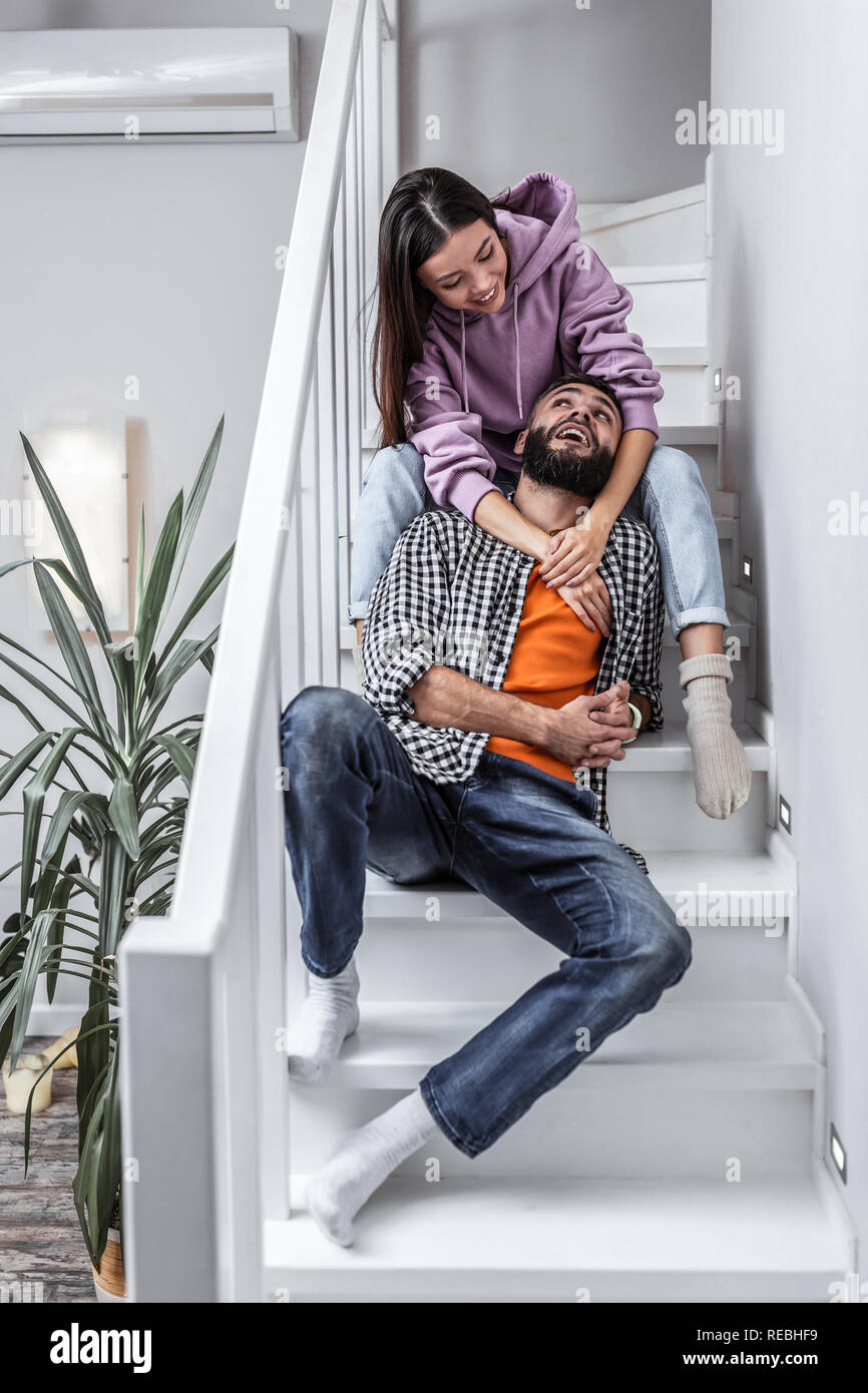 Stylish loving couple sitting on stairs while resting at home Stock ...