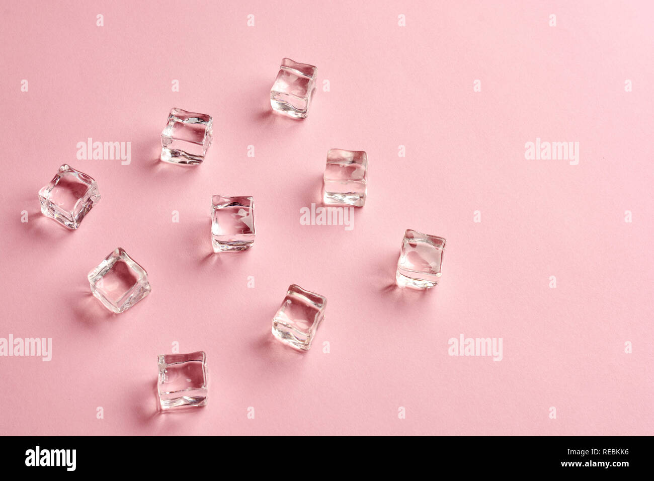 Set pieces of pure ice cubes on pink background with copy space. Top ...