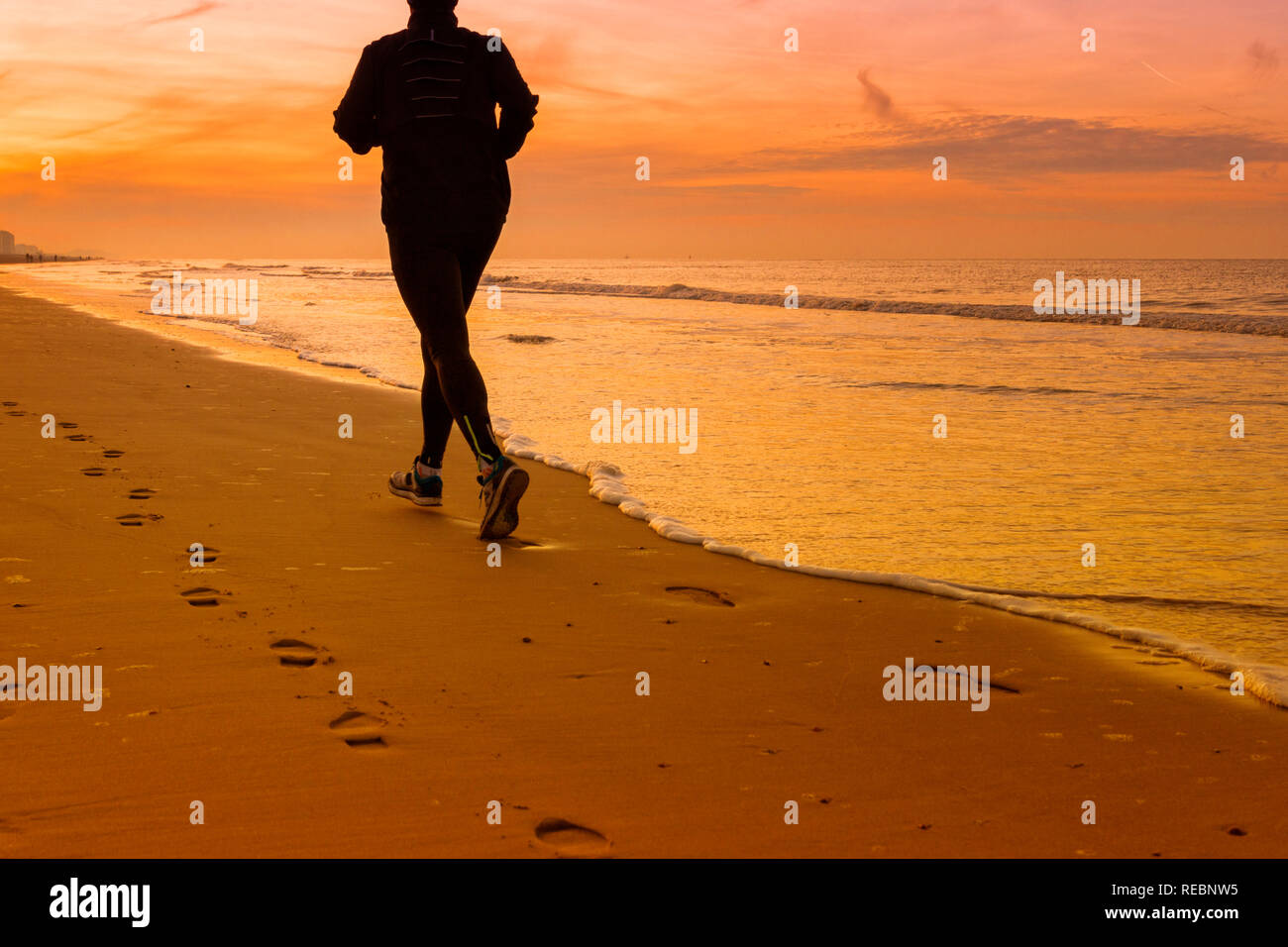 Silhouette of a jogger running on a beach at sunset Stock Photo - Alamy