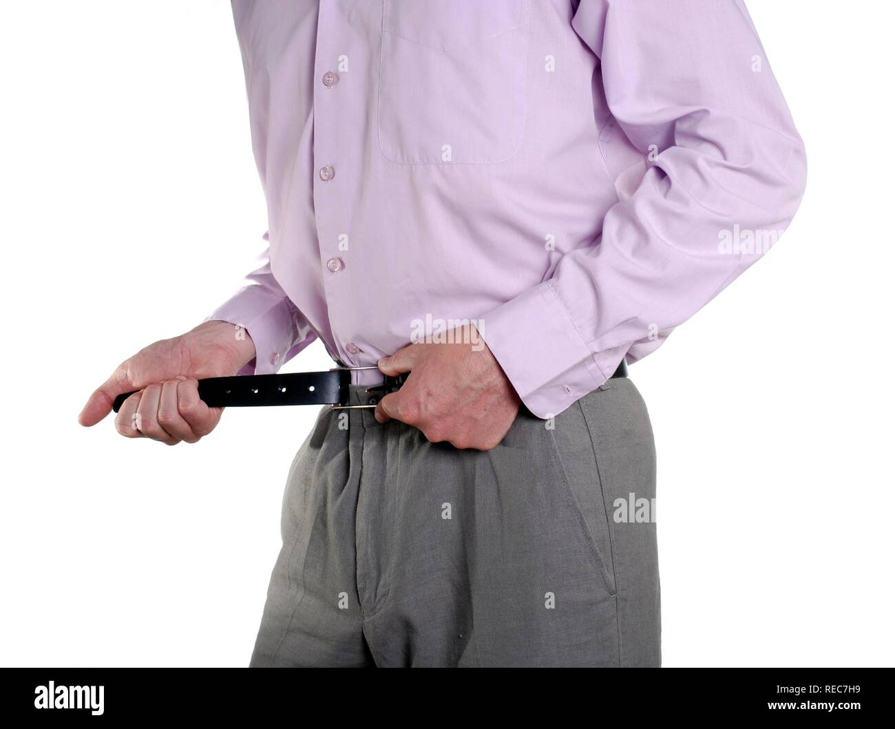 Business man tightening his belt during tough economic times ...