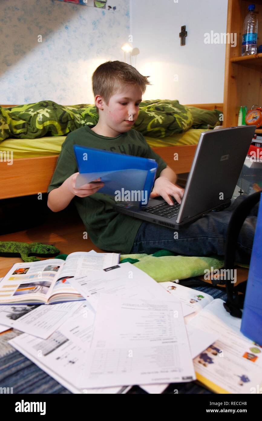Boy, 11, working with his computer at home in his bedroom doing school ...