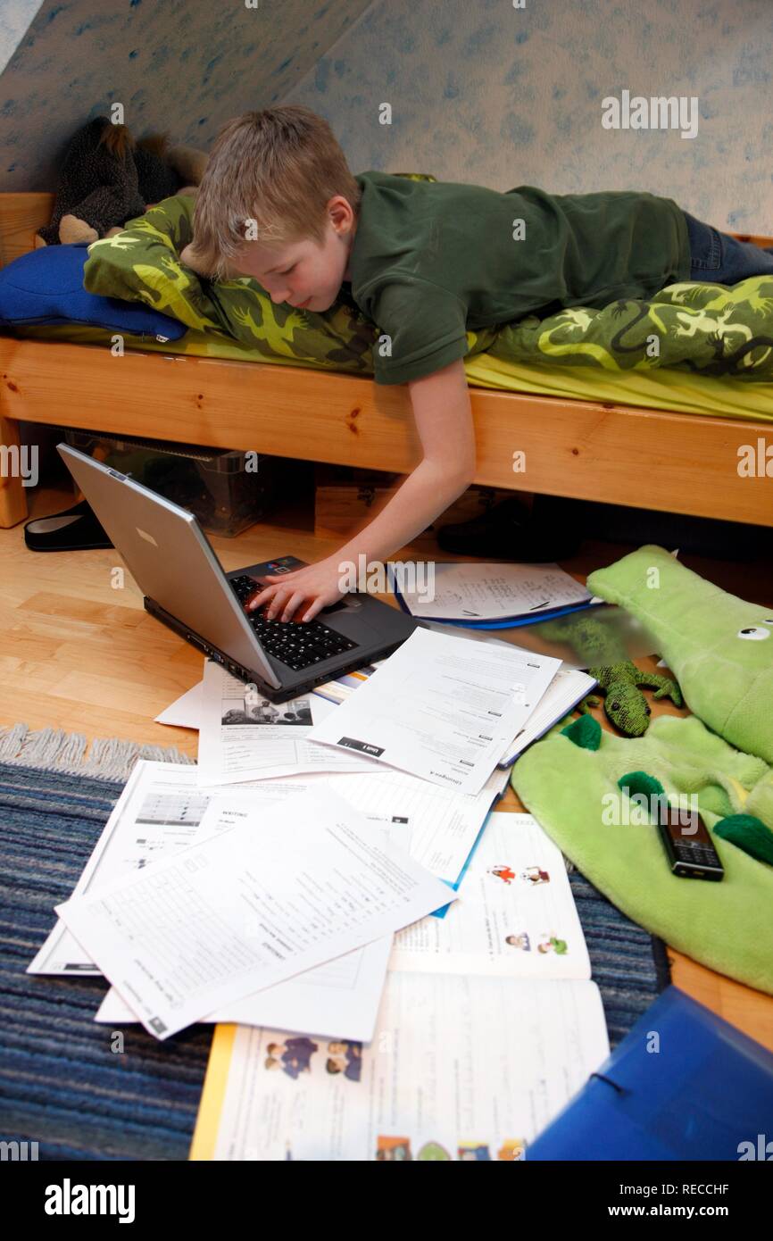 Boy, 11 years old, working with his computer at home in his room, doing ...