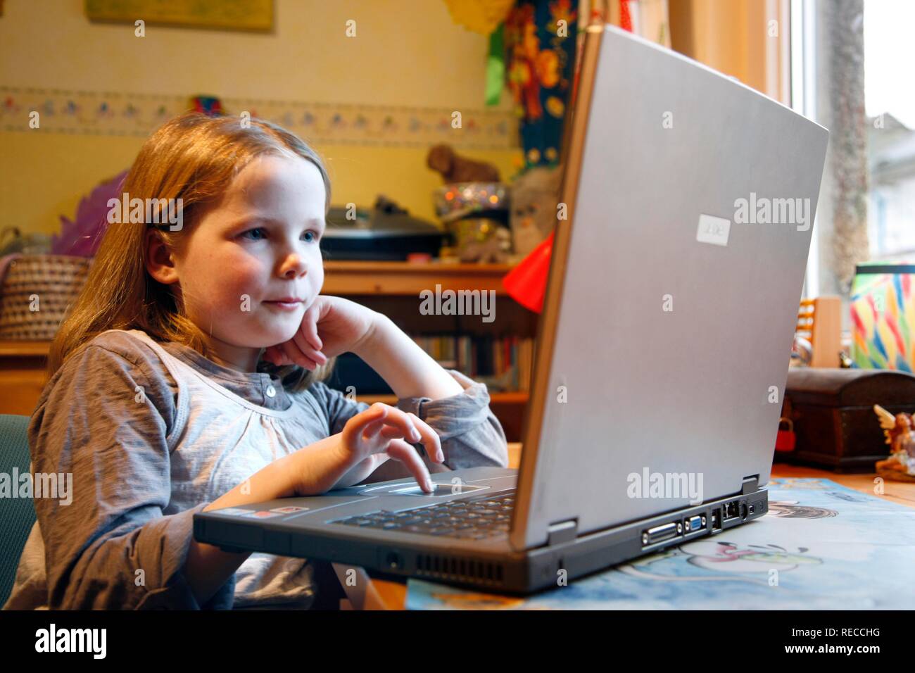 Girl, 7 years old, working with a computer at home in her room, doing ...