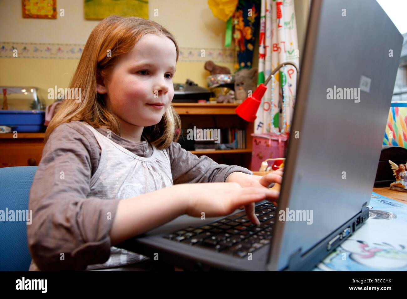 Girl, 7 years old, working with a computer at home in her room, doing ...