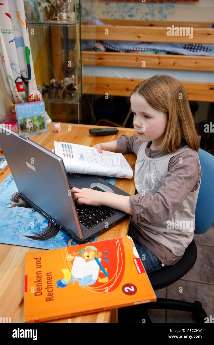 Girl, 7 years old, working with a computer at home in her room, doing ...