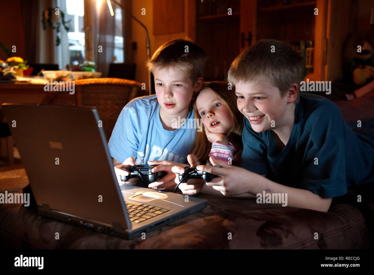 Siblings, 7, 11, 13 years old, with laptop computer in the living room ...