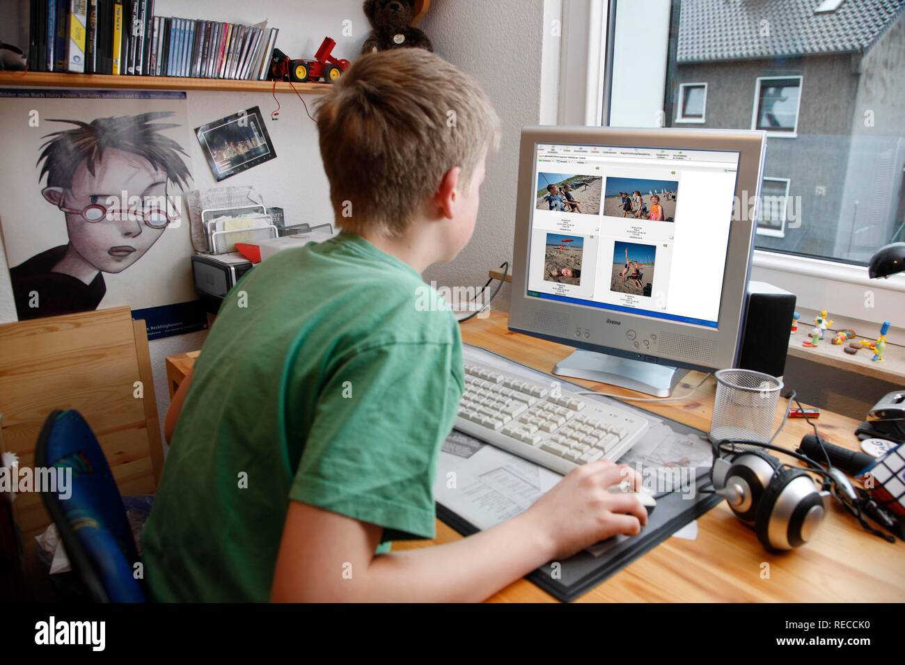 Boy, 13, working with his computer at home, viewing holiday photos in ...