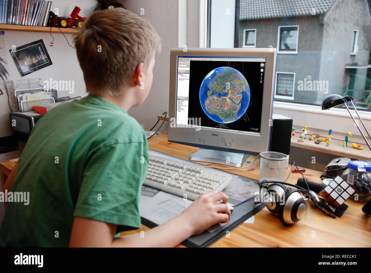 Boy, 13, working with his computer at home, surfing with Google Earth ...