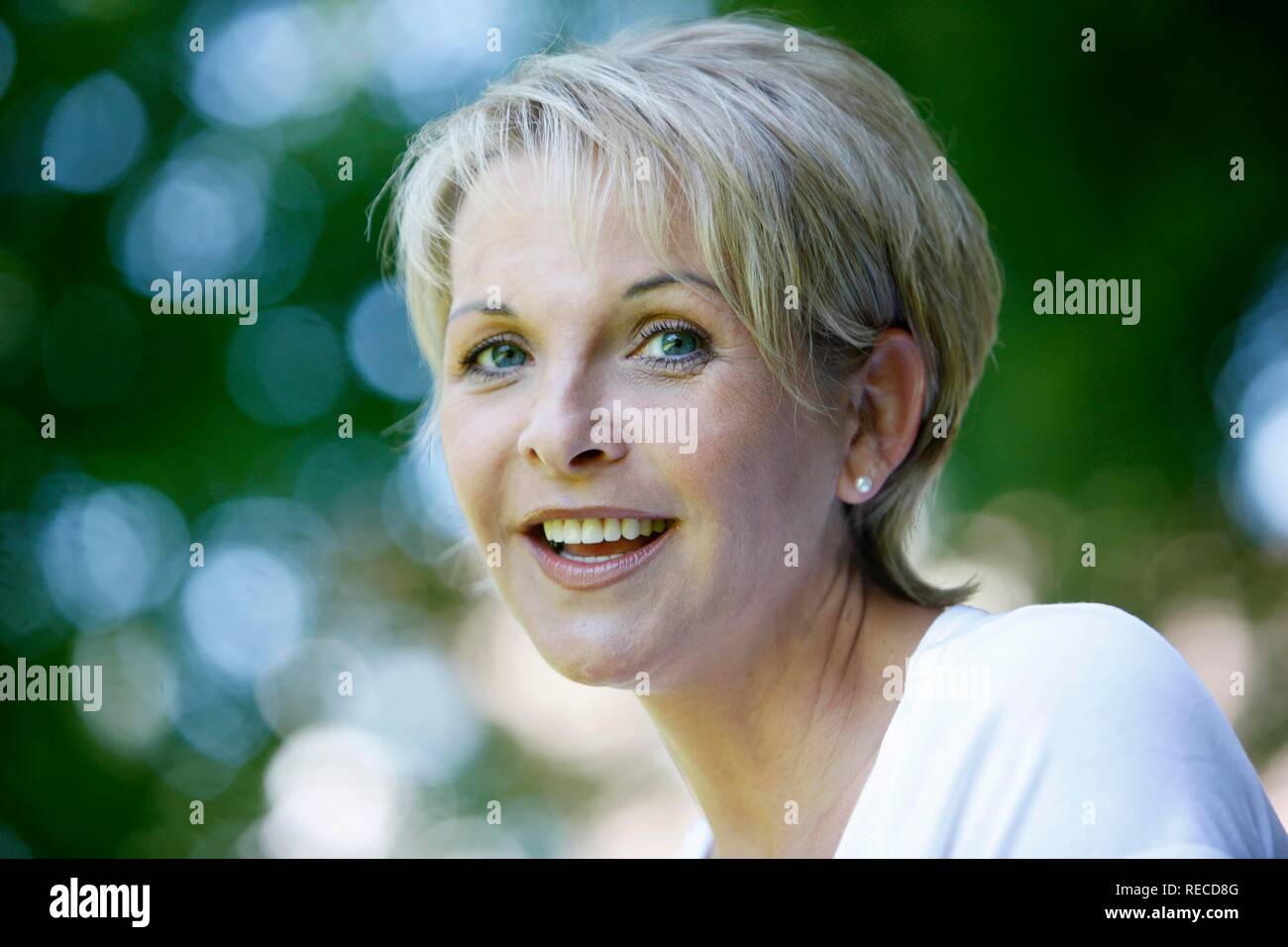 Portrait of a woman, early 40s, in the garden, looking at the camera ...