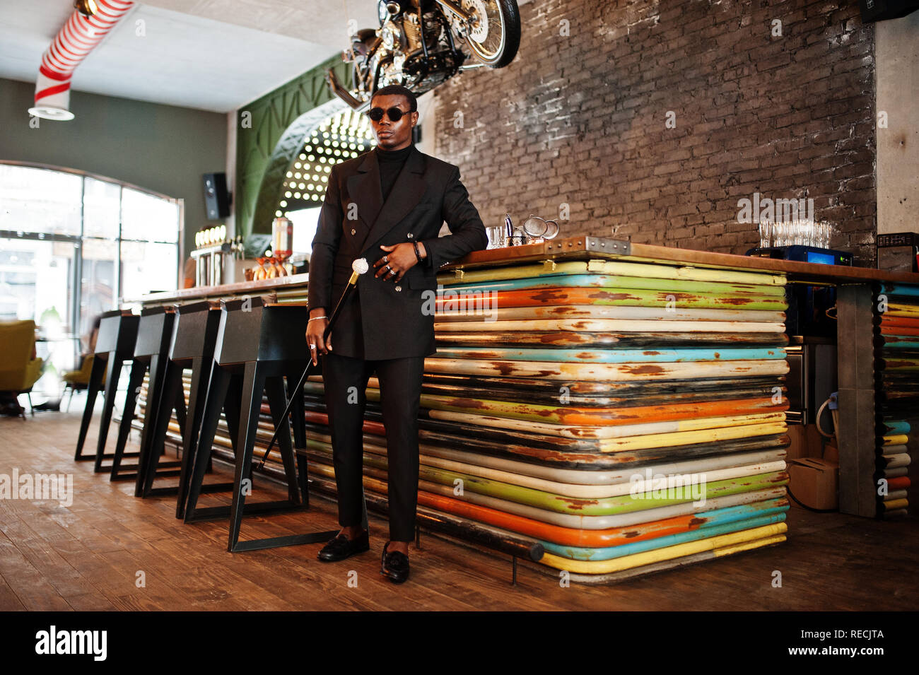Stylish african american gentleman in elegant black jacket and sunglasses, holding retro walking ...