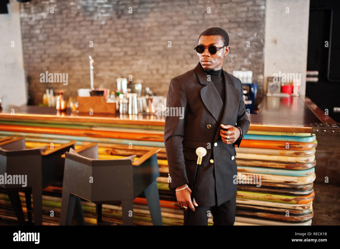 Stylish african american gentleman in elegant black jacket and sunglasses, holding retro walking ...