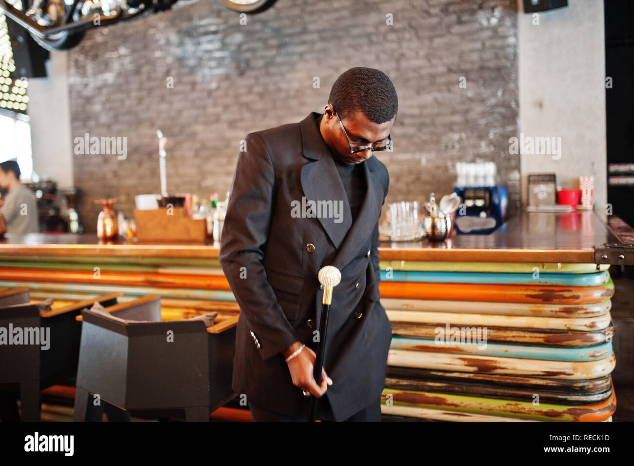 Stylish african american gentleman in elegant black jacket and sunglasses, holding retro walking ...