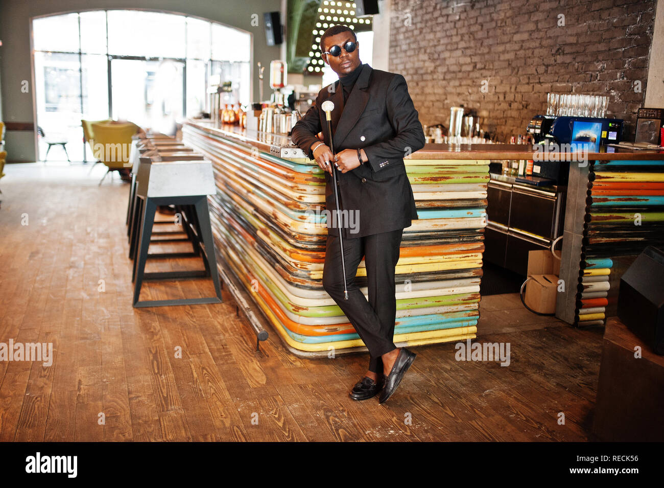 Stylish african american gentleman in elegant black jacket and sunglasses, holding retro walking ...