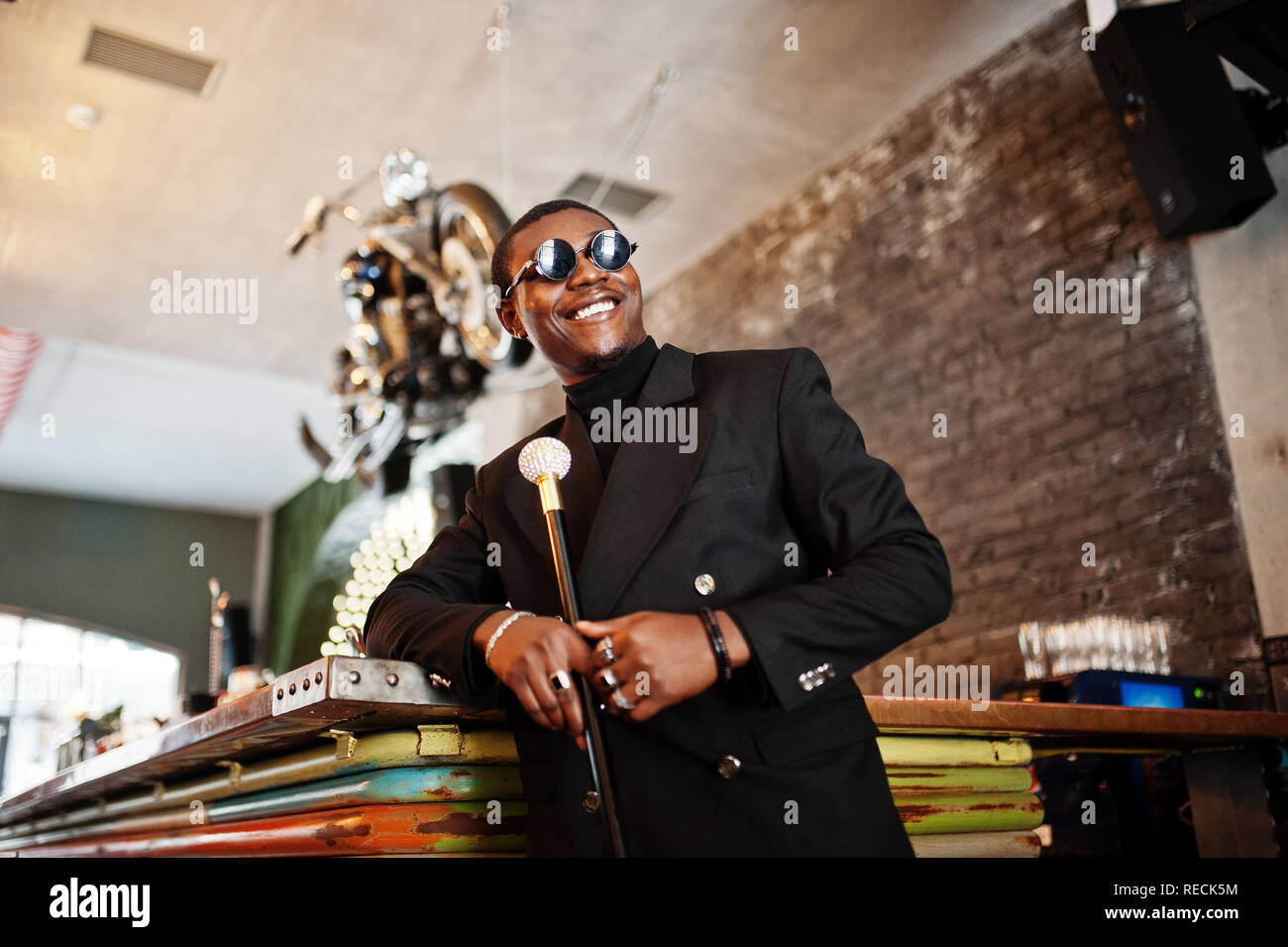 Stylish african american gentleman in elegant black jacket and sunglasses, holding retro walking ...