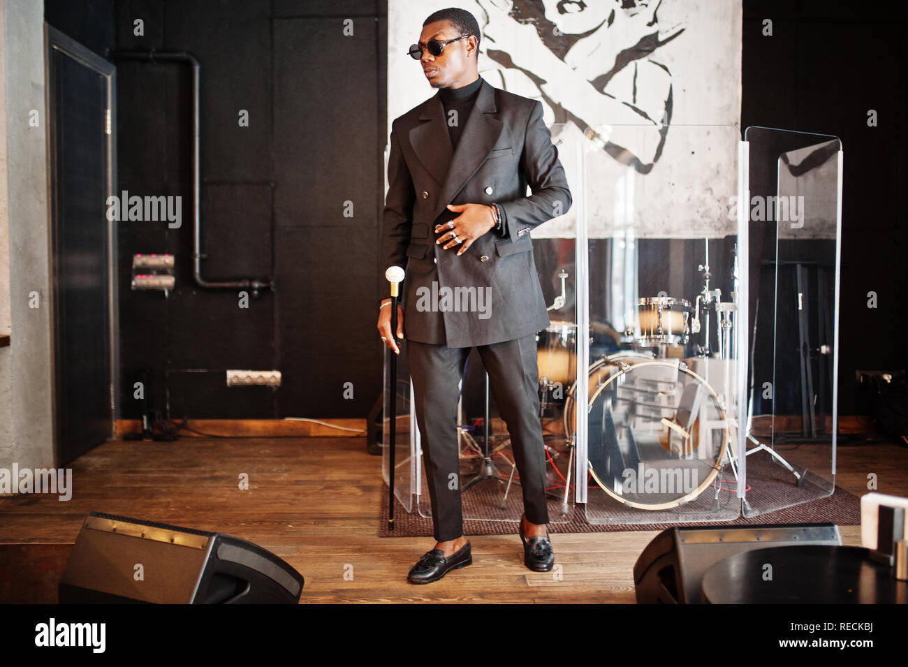 Stylish african american gentleman in elegant black jacket and sunglasses, holding retro walking ...
