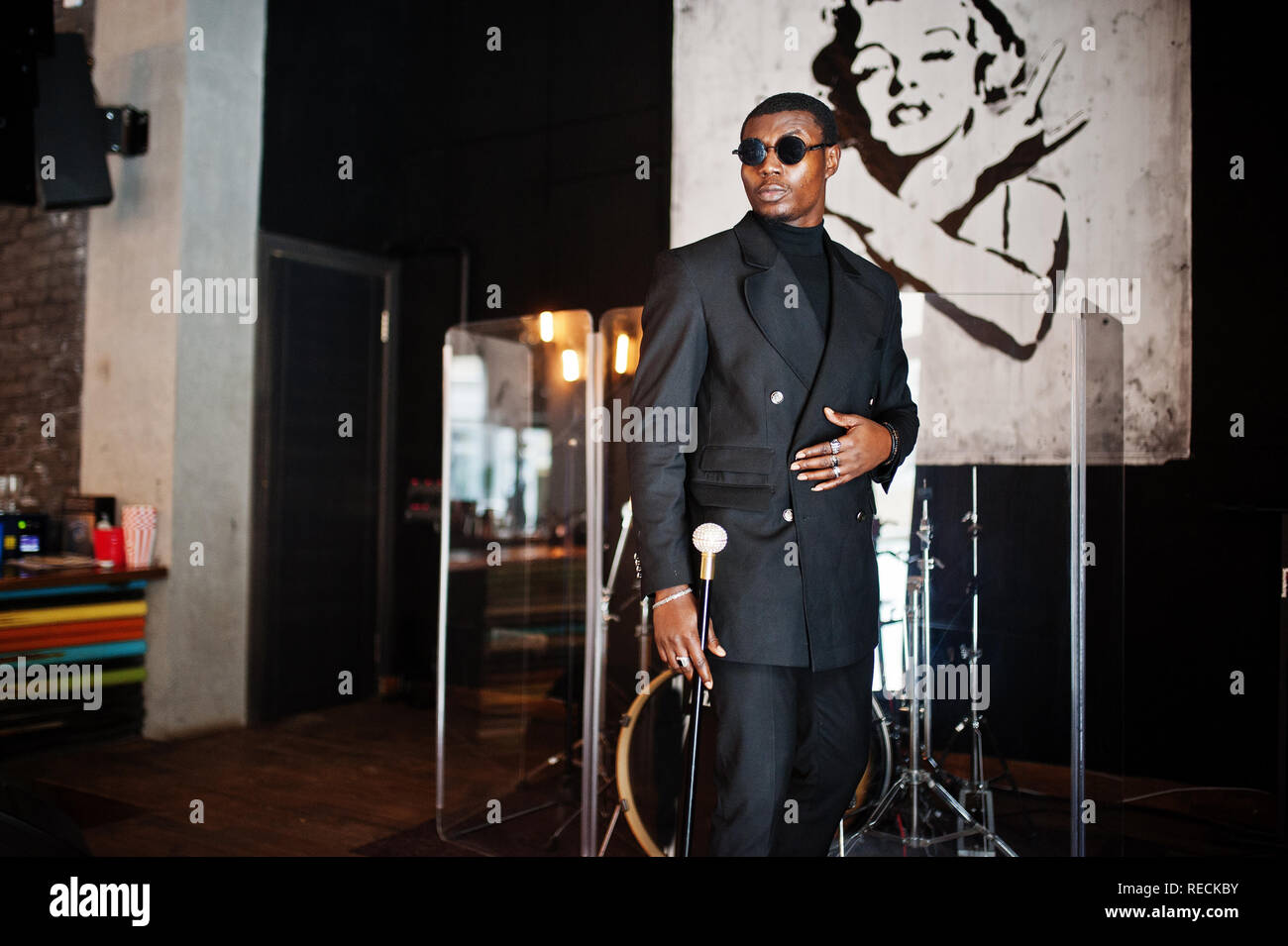 Stylish african american gentleman in elegant black jacket and sunglasses, holding retro walking ...