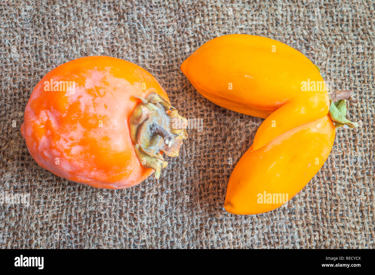 Top view of bright orange Persimmons fruit kept on a jute mat. One ...