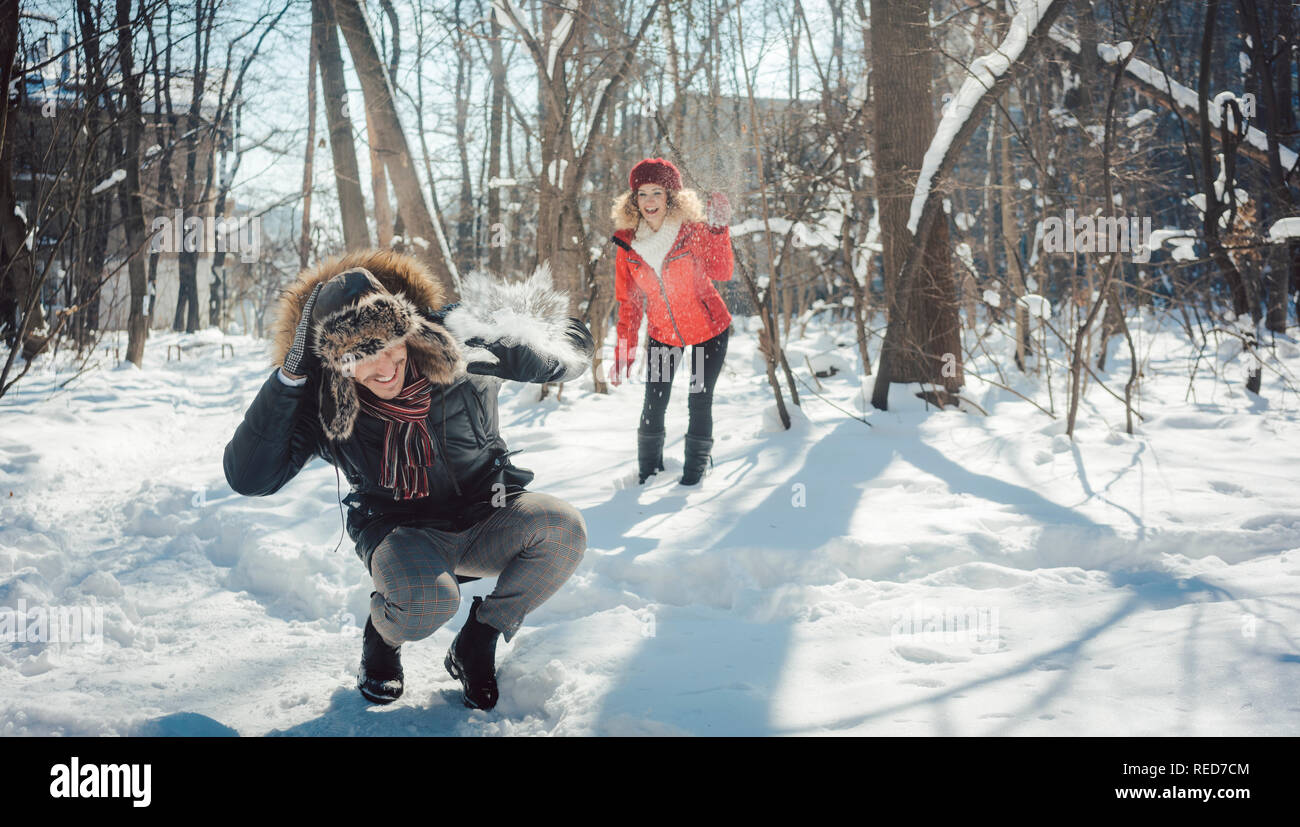 Woman throwing snowball on her guy in winter in playful mood Stock ...