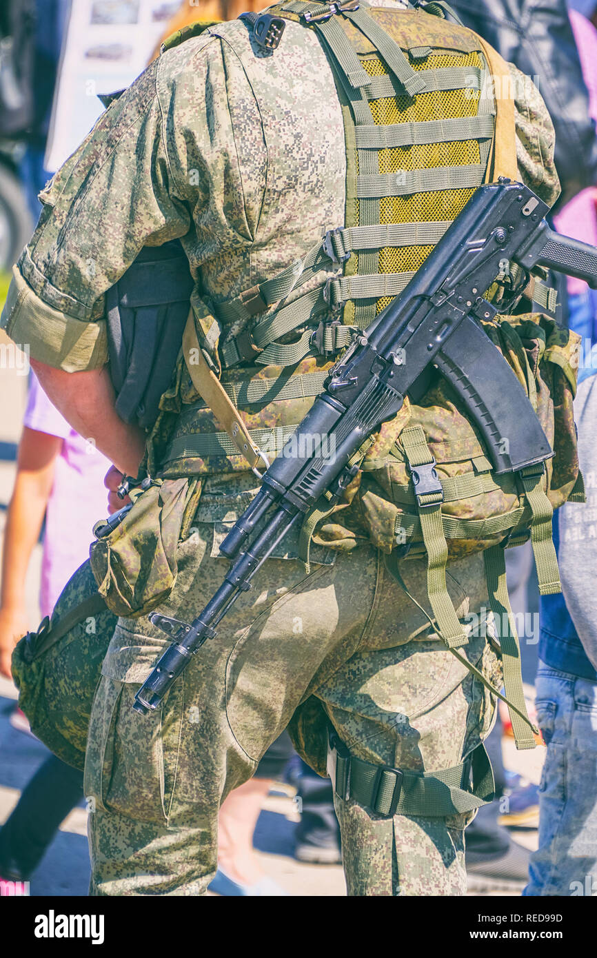 Soldier in camouflage with a gun behind his back Stock Photo - Alamy