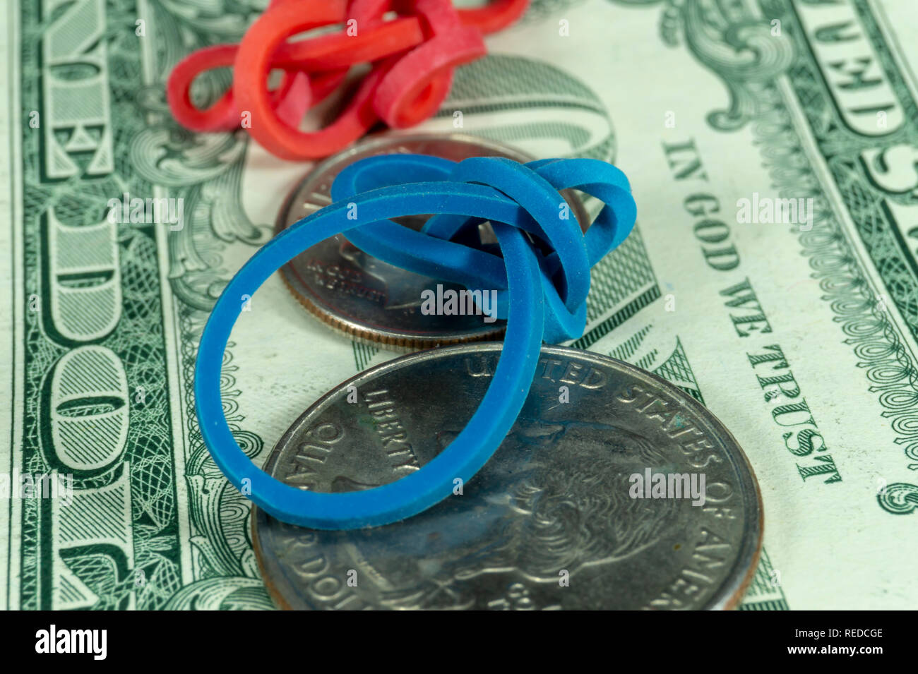 Twisted red blue rubber bands and coins on dollar bills in a close up ...