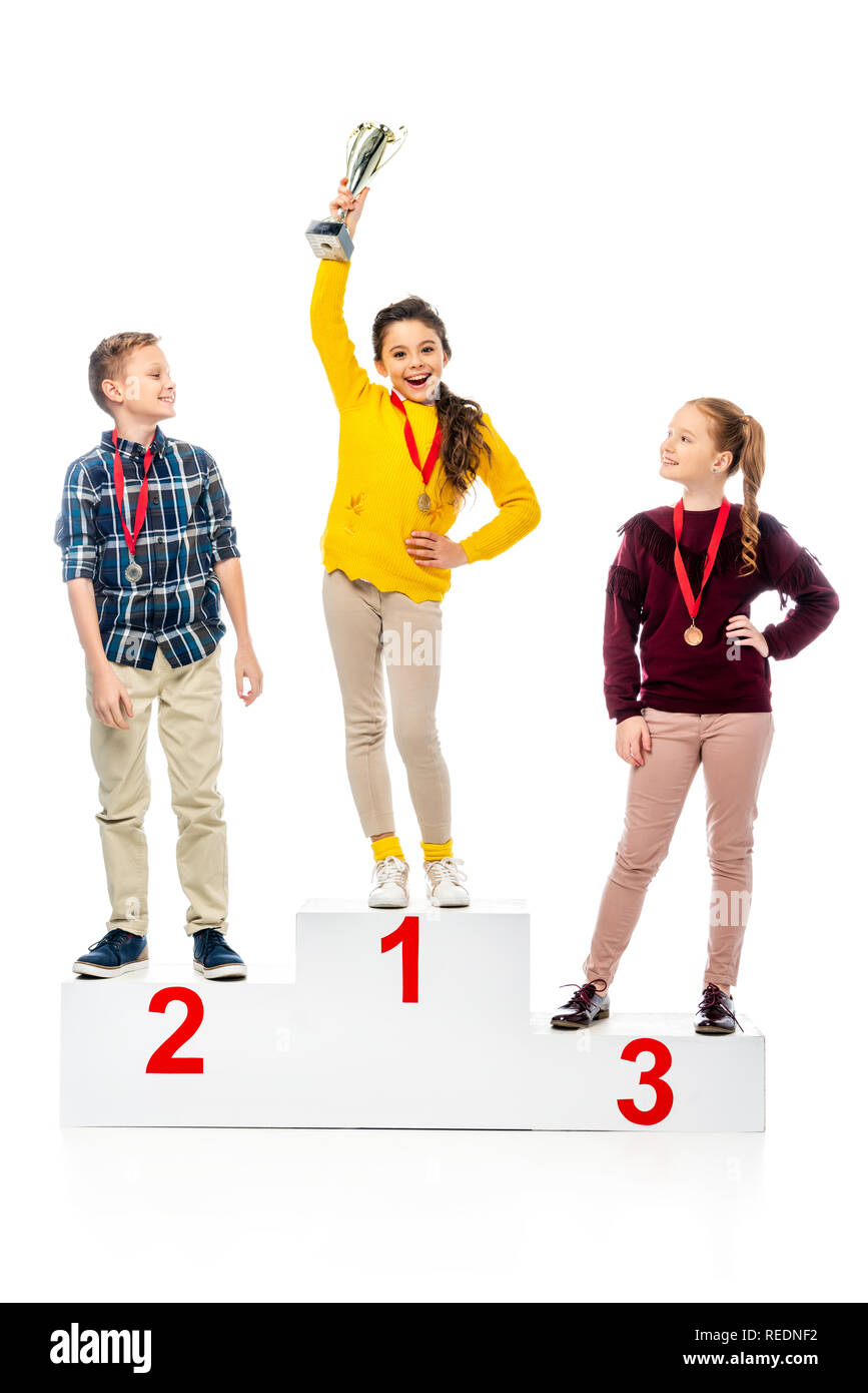 schoolchildren with medals standing on winner podium and looking at ...