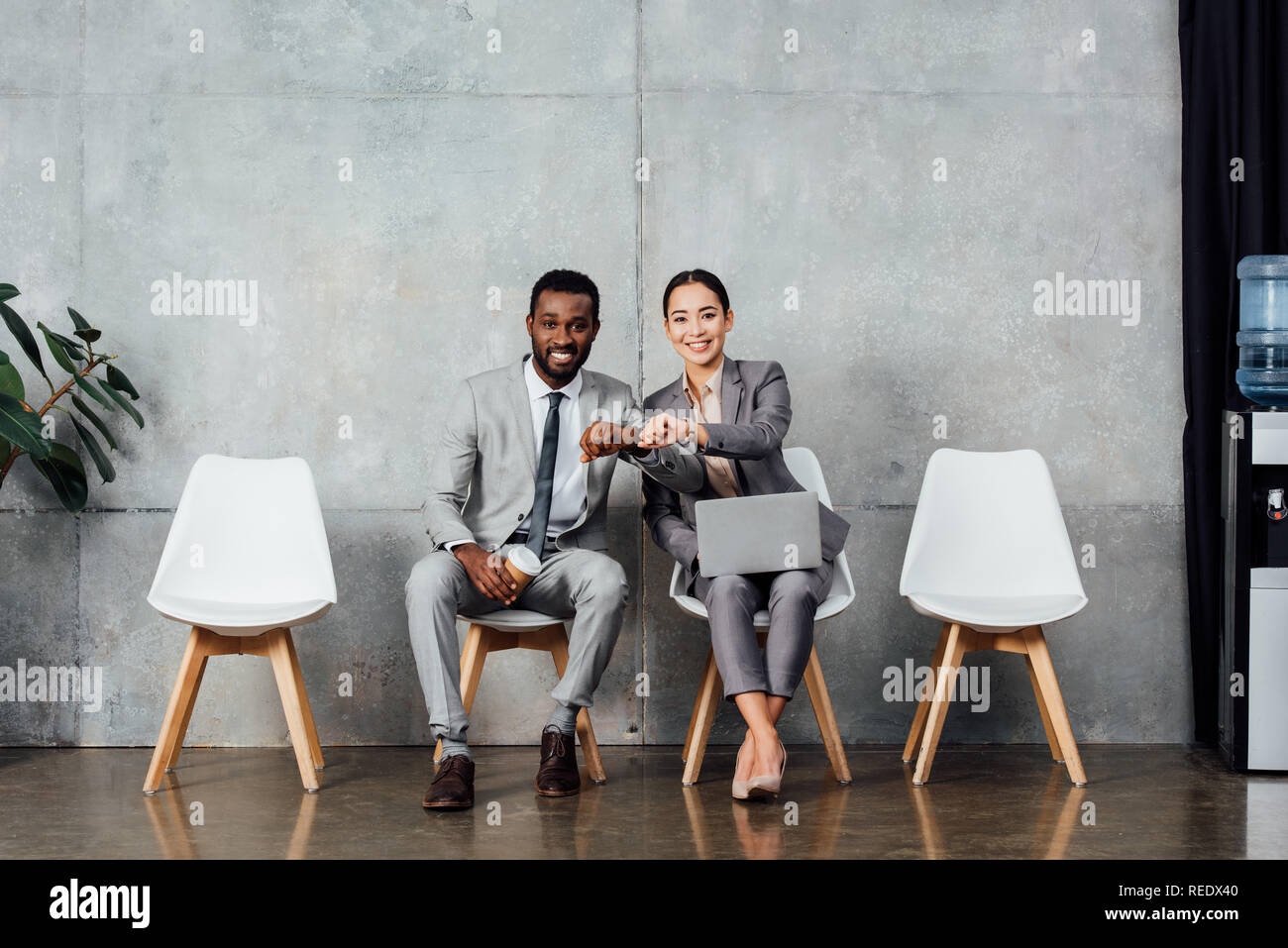 smiling multiethnic colleagues with laptop and coffee sitting and ...